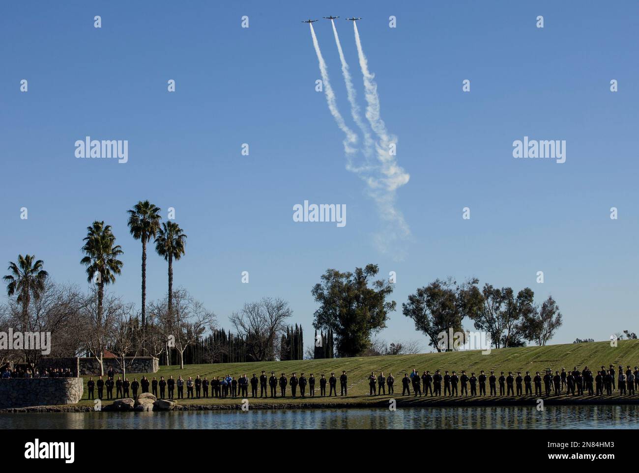 Police officers stand in attention as planes flyover in formation ...