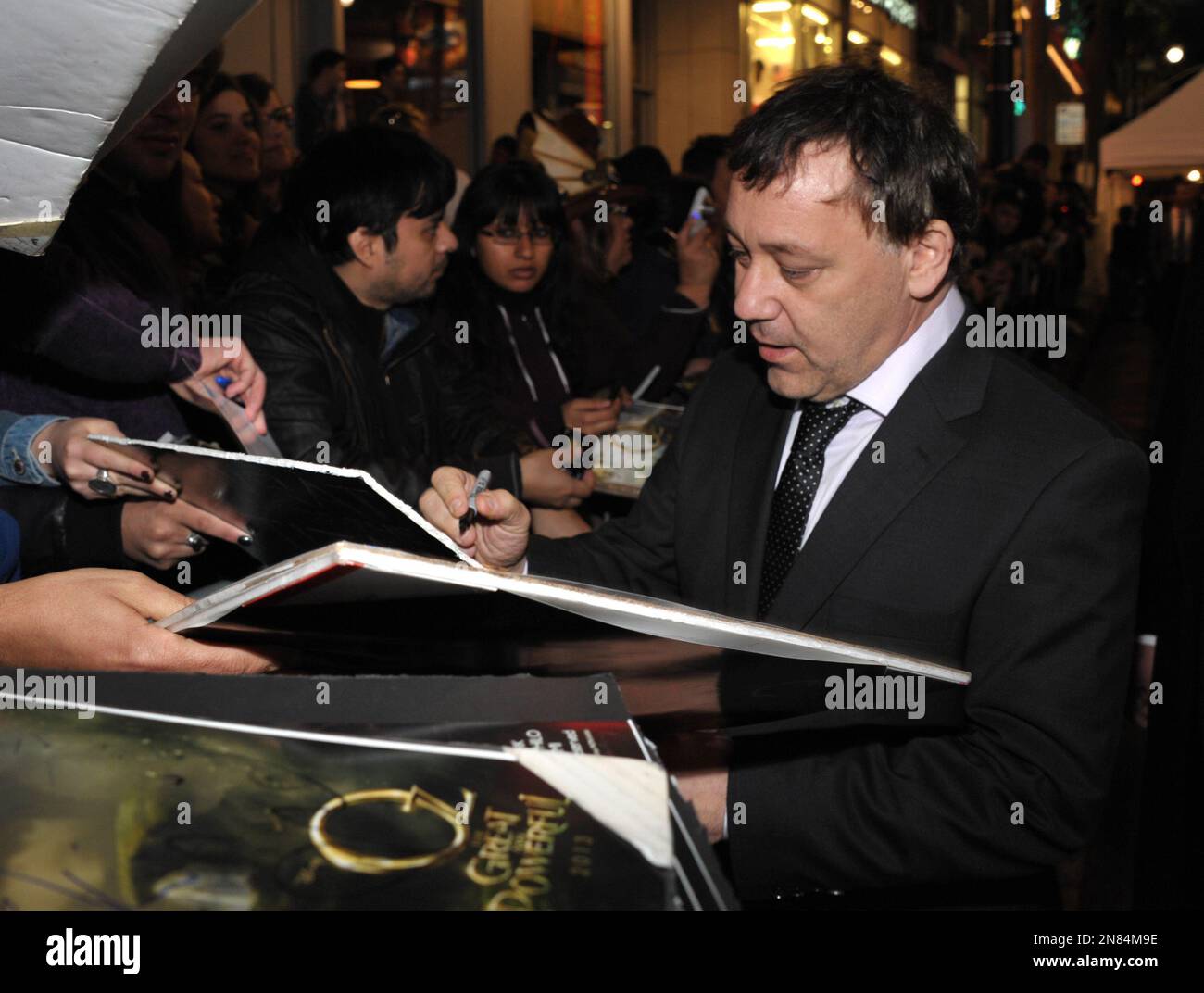 Sam Raimi signs autographs as he arrives at the world premiere of "Oz ...