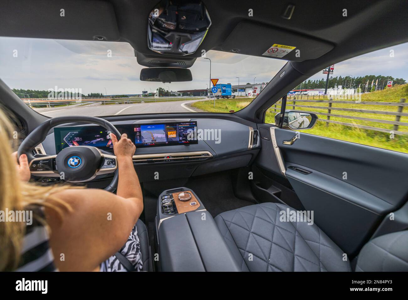 Beautiful interior view of electric car BMW iX40 on road. Female driver ...