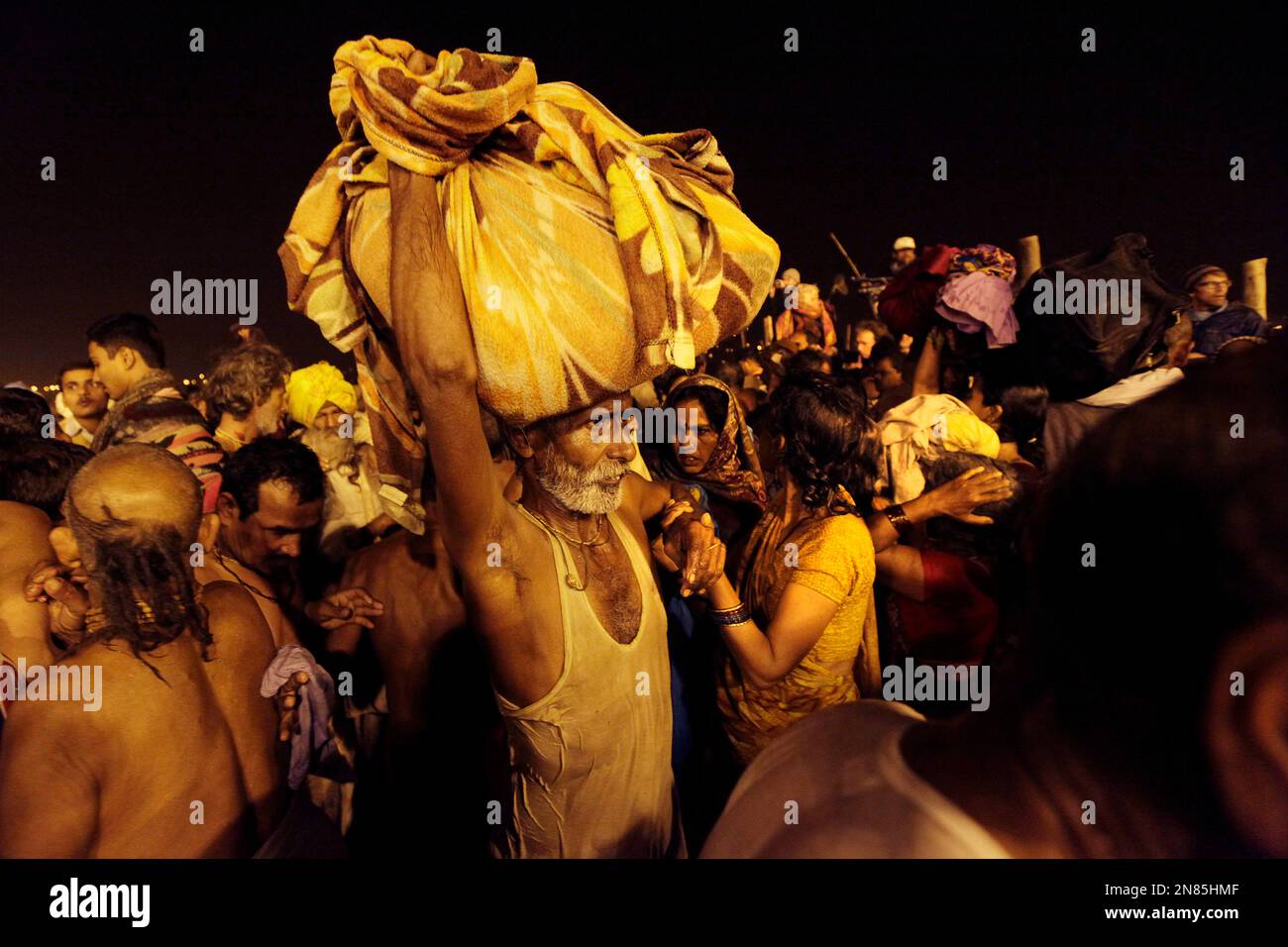 A Hindu devotee waits with the bundle of cloths of his relatives on at ...
