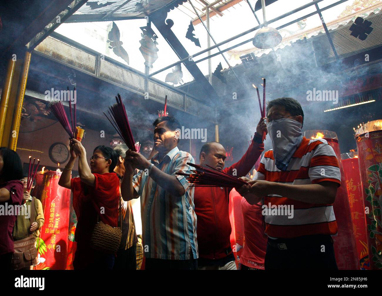 Indonesian ethnic Chinese burn incense sticks while praying during ...