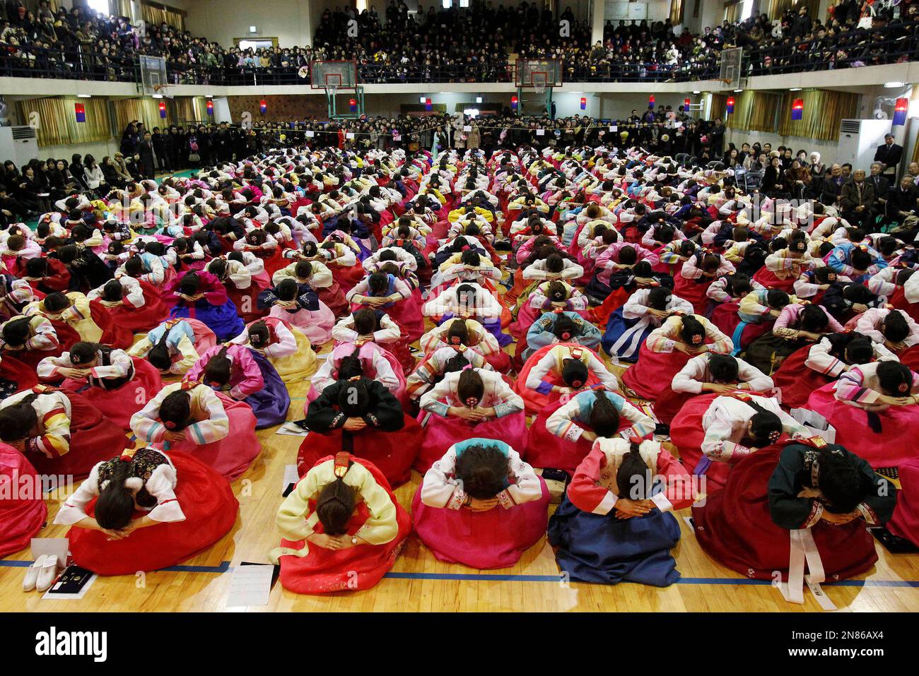 South Korean senior students clad in traditional costumes sit and bow ...