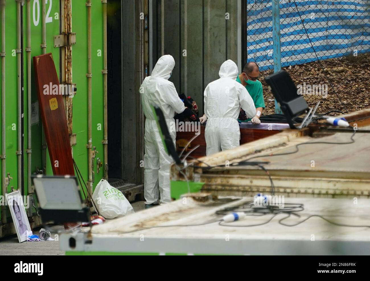 Workers transfer bodies of the deceased from a makeshift morgue outside ...