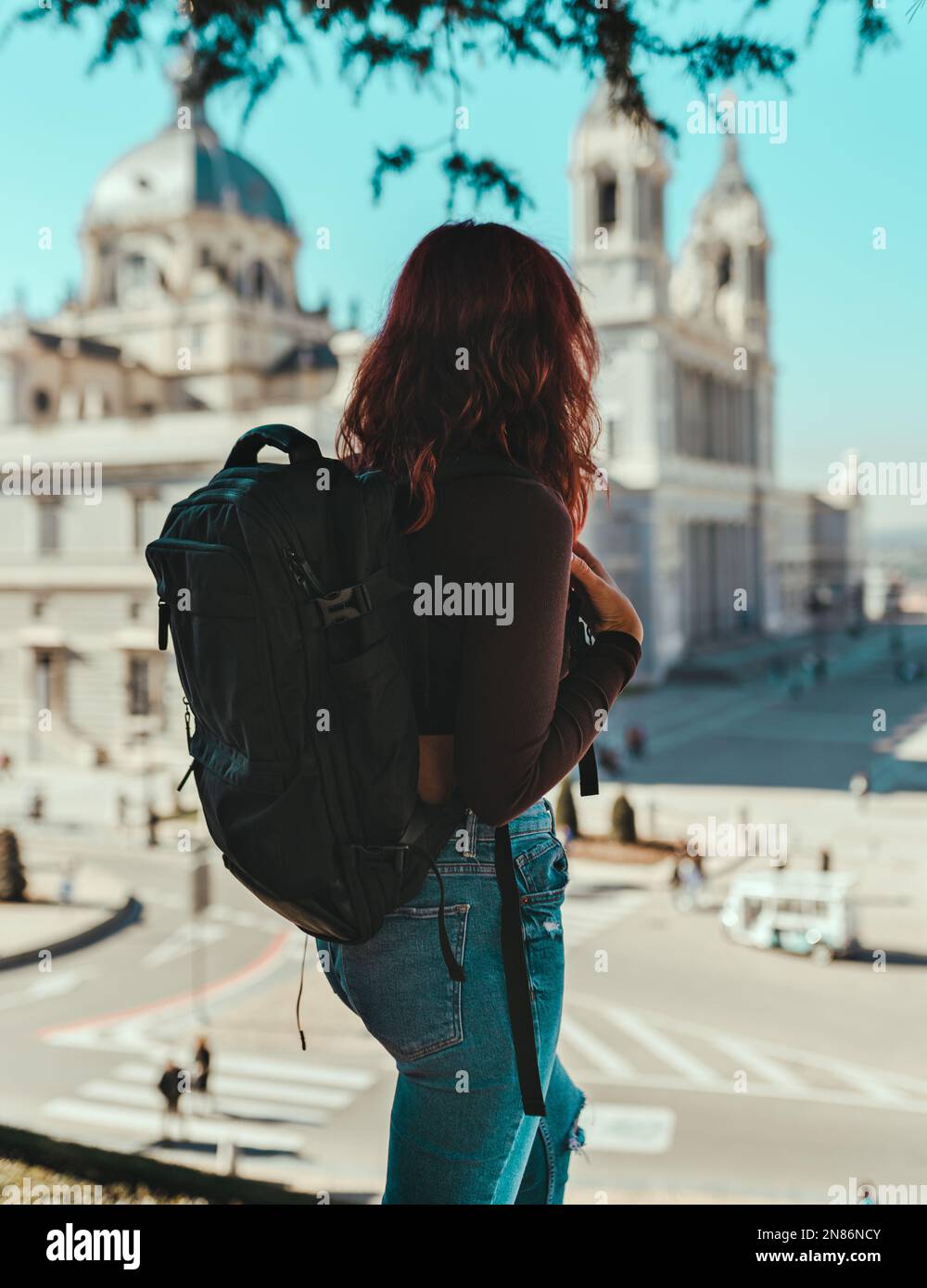 A vertical back view of a young female wearing a black backpack on the ...