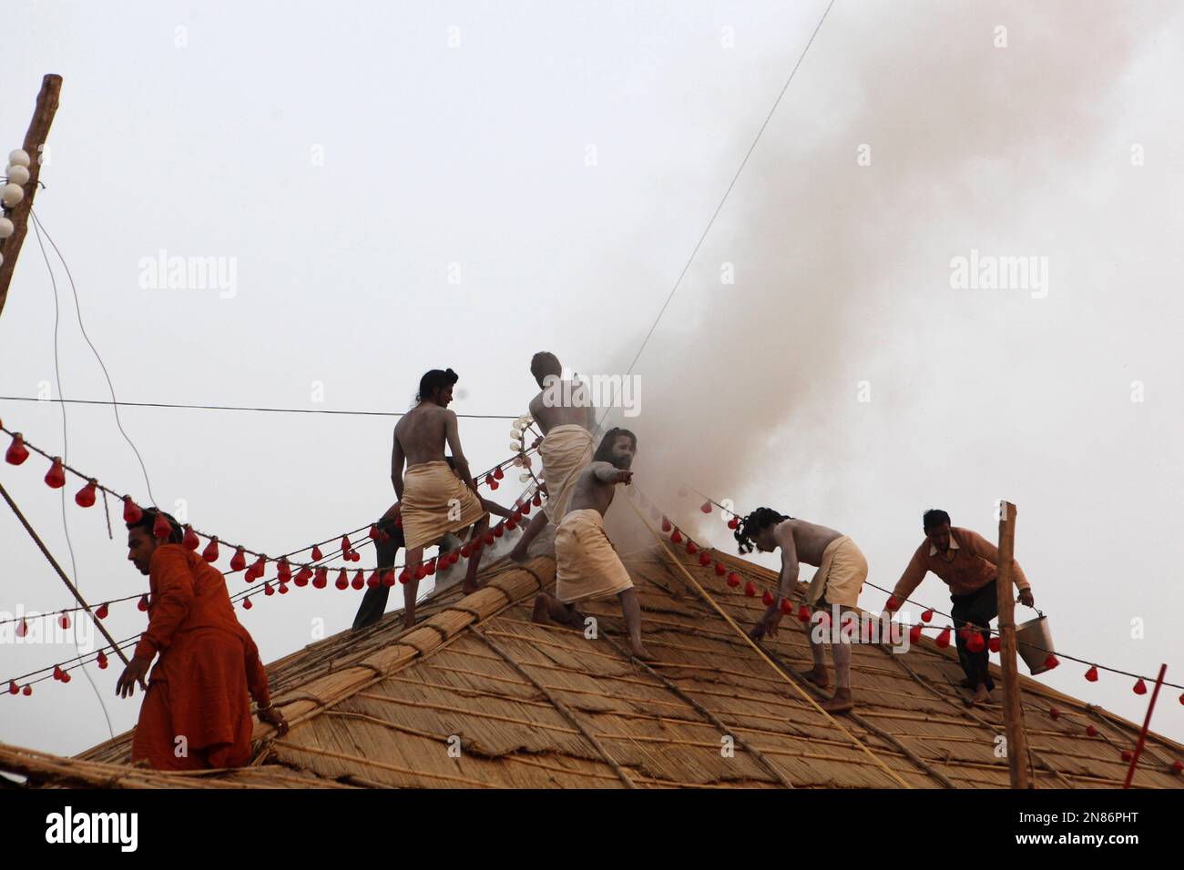 Hindu monks extinguish the fire on the roof of a temporary temple ...