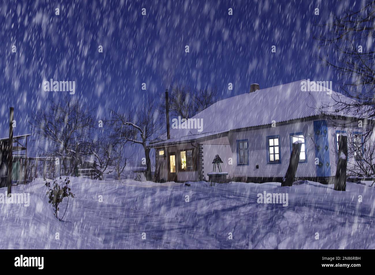 Beautiful view of the snow-covered house at night during heavy snowfall ...