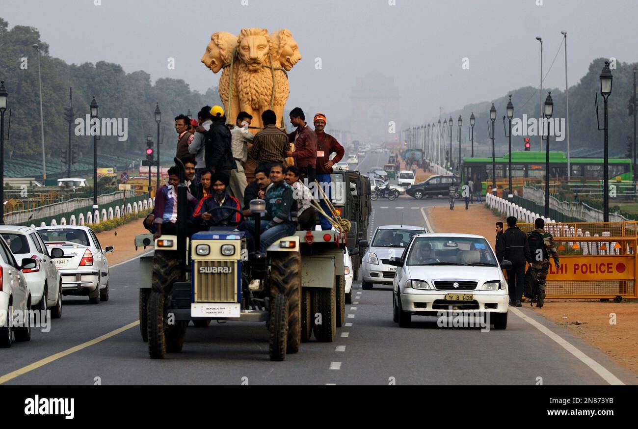 Indian municipal workers ride on a tractor trolley carrying a stone ...