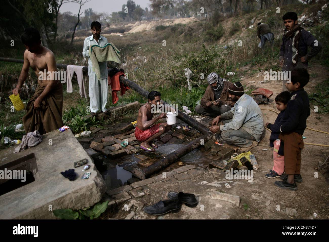 Pakistani construction workers shower using water from a broken pipe ...