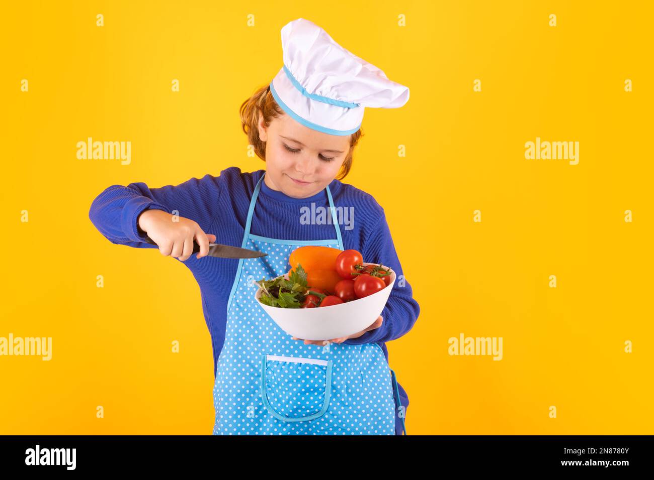 Kid cook hold plate with vegetables. Child chef cook prepares food on ...