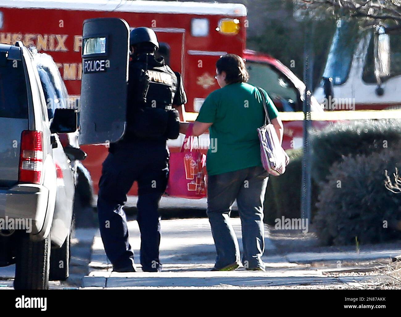 A member of the Phoenix Police Department SWAT team leads a female ...