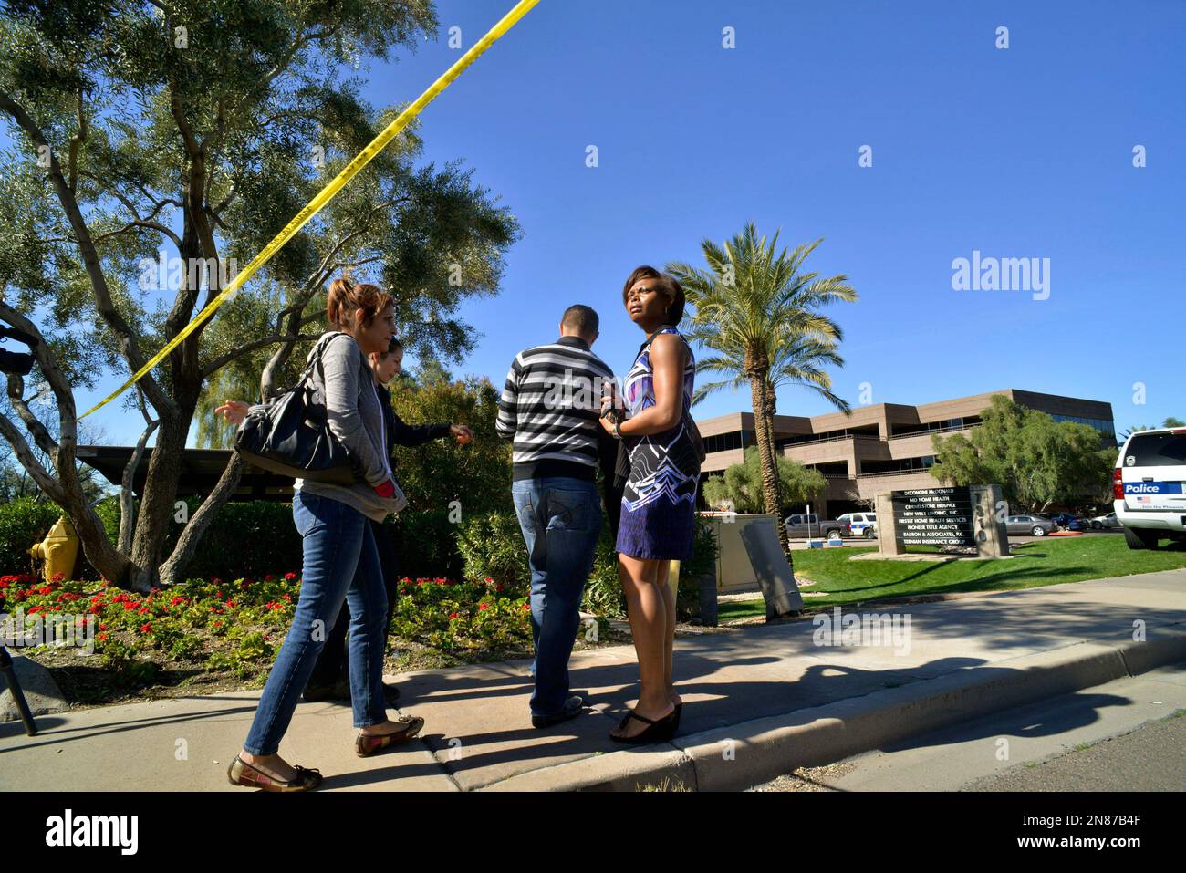People are escorted back into an office building by a police officer ...