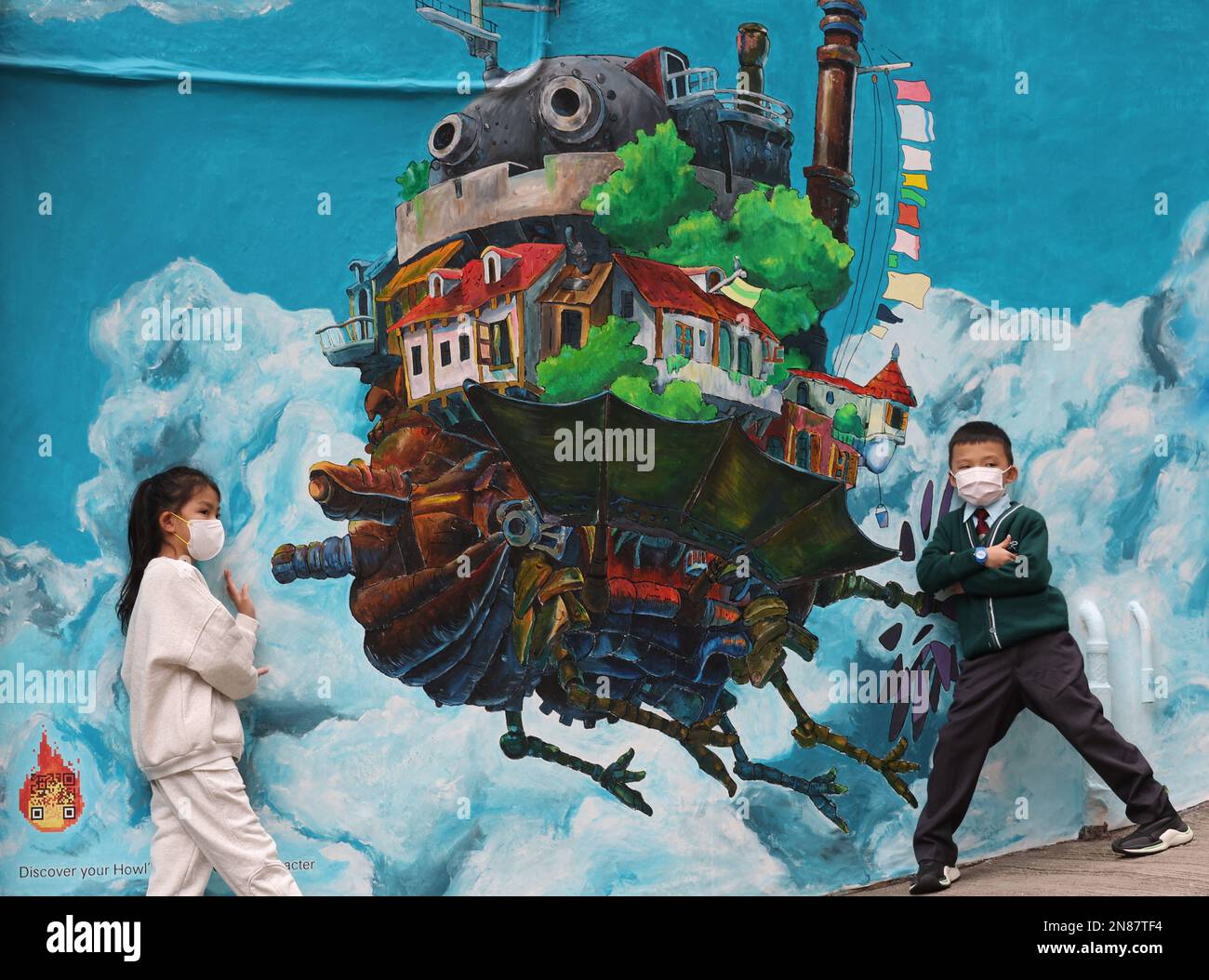 Children pose for a picture in front of a mural featuring Howl's Moving ...