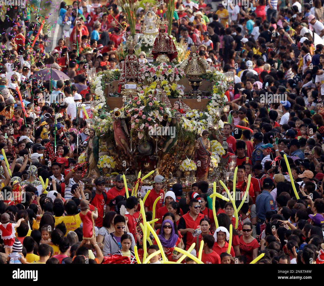 Hundreds of devotees watch as a float with images of the Infant Jesus ...
