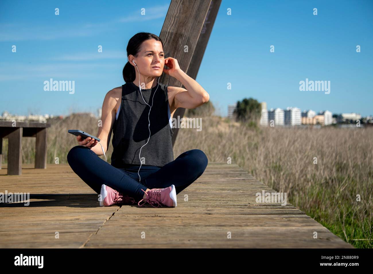 Female runner resting after exercise, sitting listening to music Stock ...