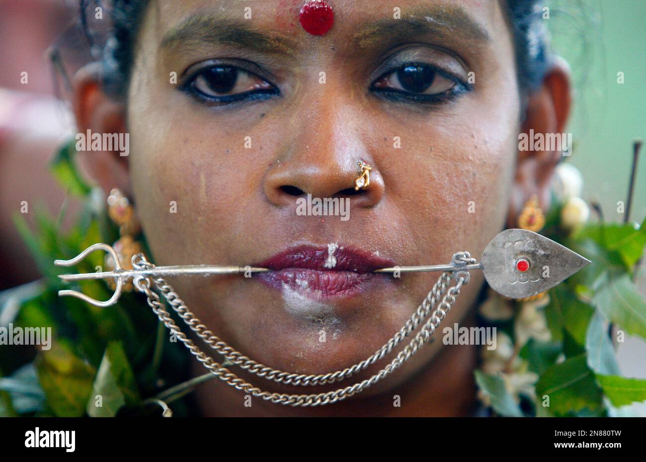 A Hindu devotee stands after getting her tongue pierced with a metal ...