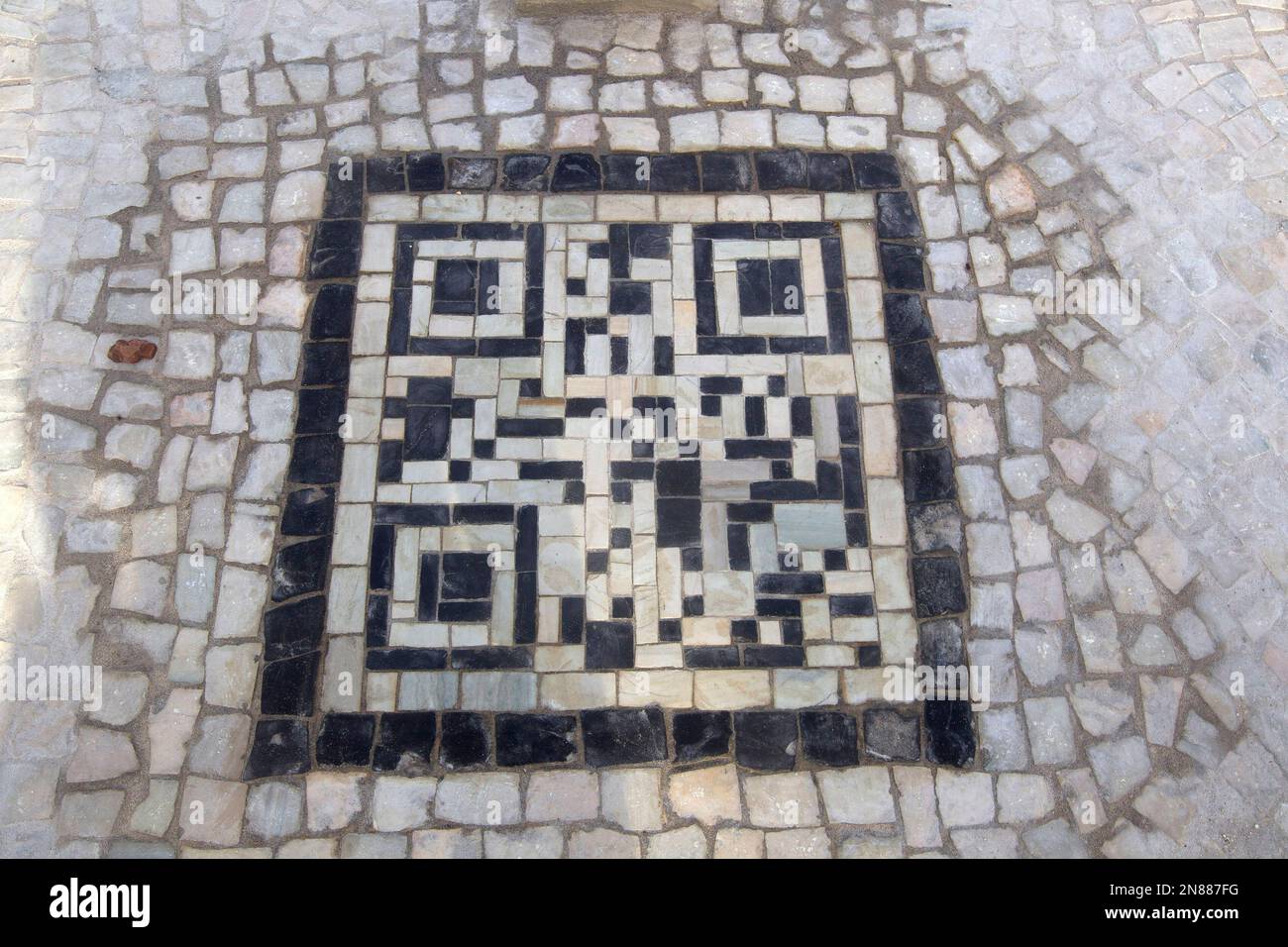 A QR codes made of the black and white stones covers a sidewalk near ...