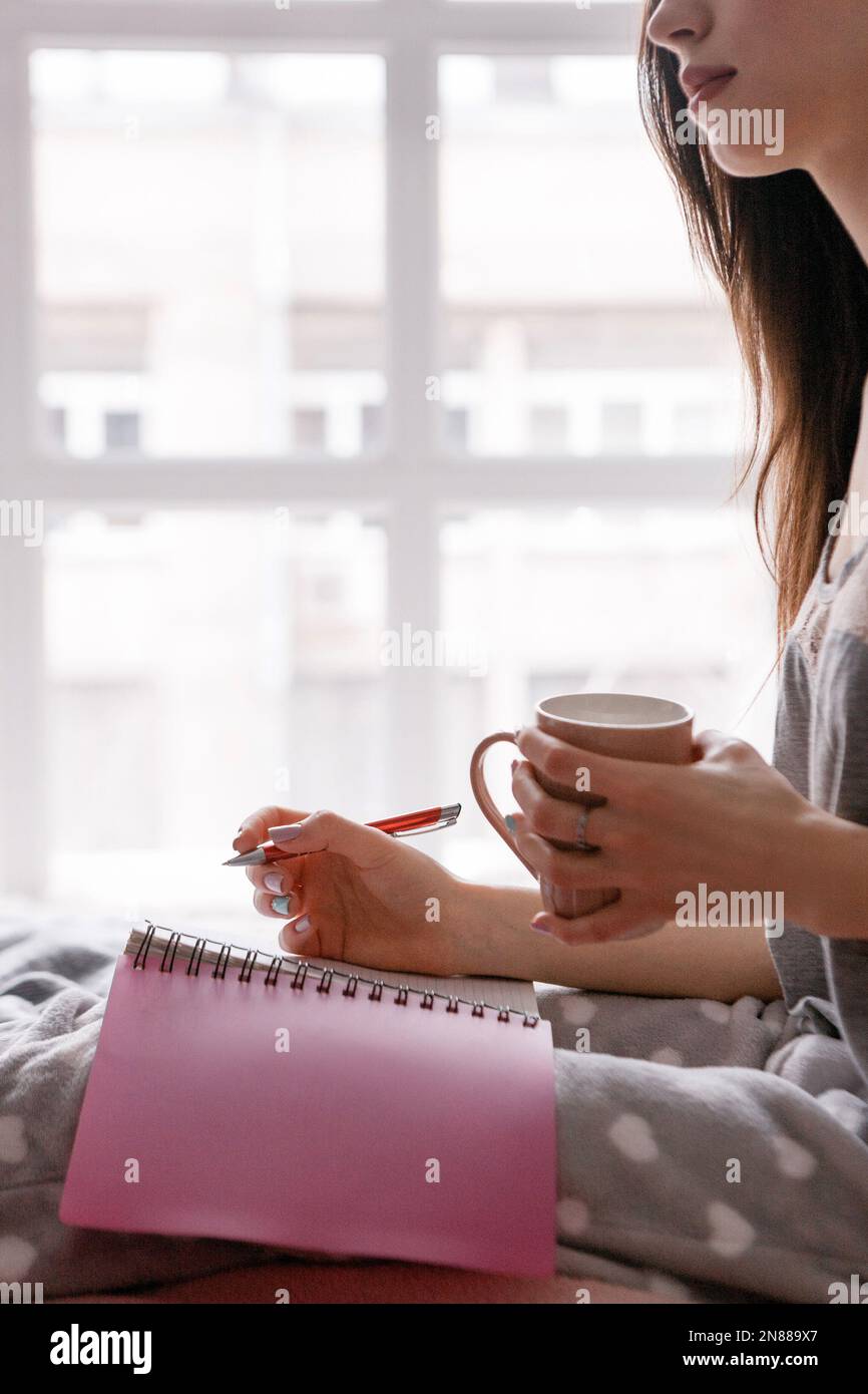 Young woman makes notes in writing book Stock Photo - Alamy