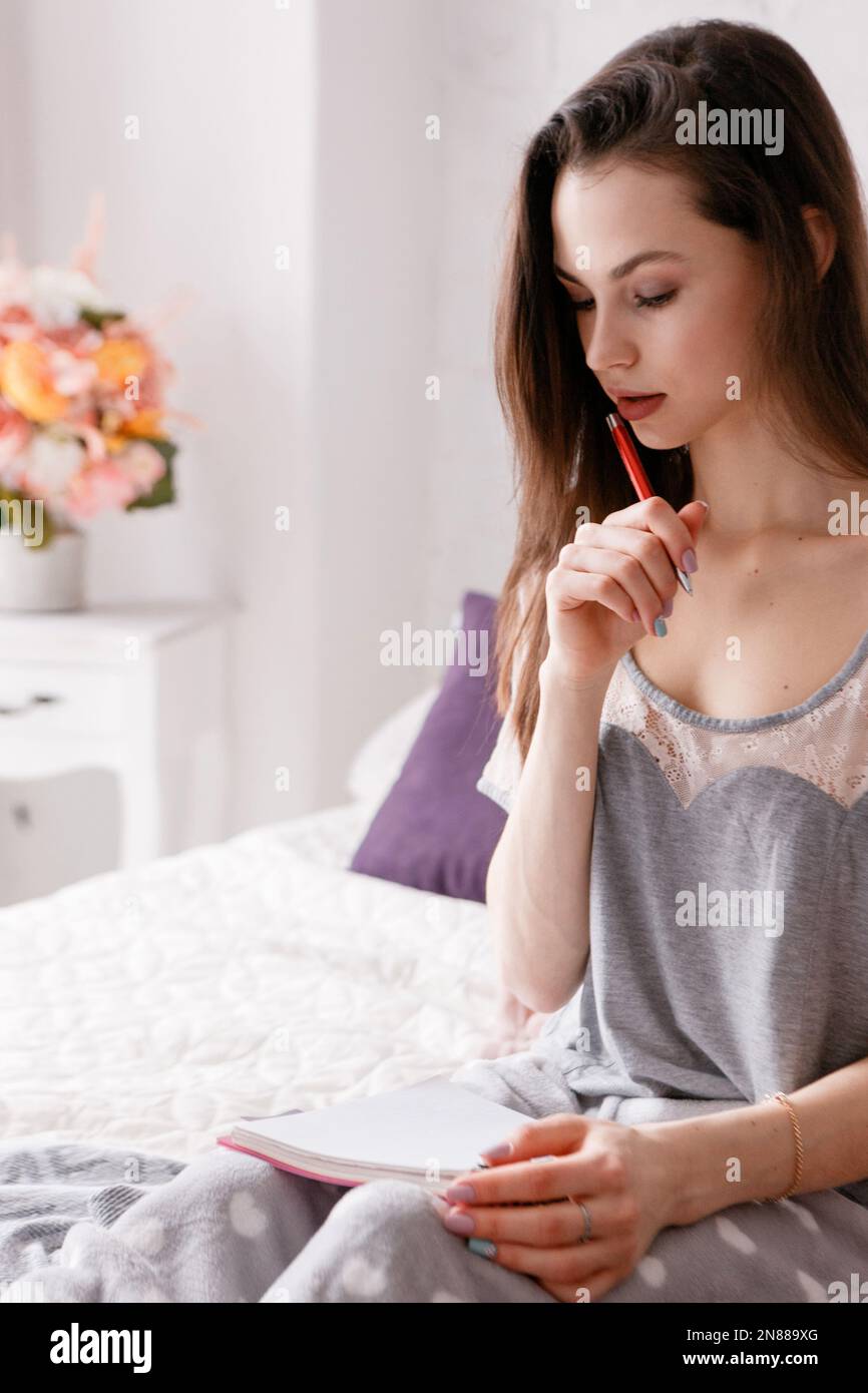 Beautiful young woman makes notes in writing book Stock Photo - Alamy