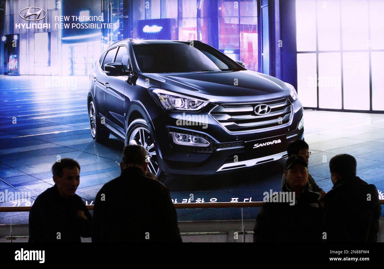 People stand in front of an advertisement for Hyundai Motor's Satafe at ...
