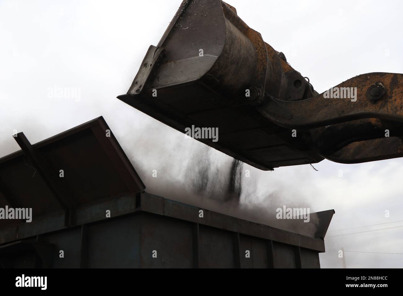 An excavator digging the ground and loading black dust for construction ...