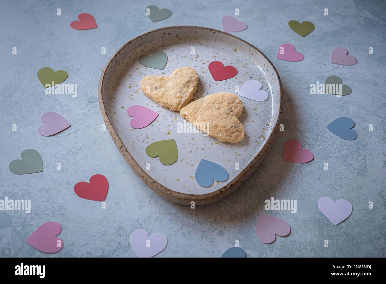 Two heart shaped shortbread biscuits on a ceramic platter surrounded by ...