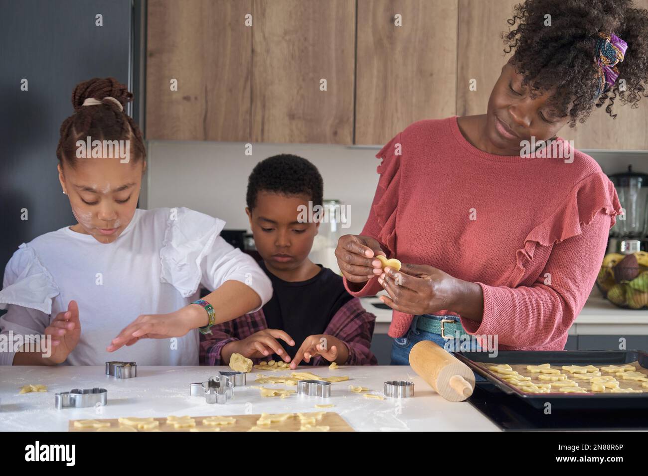 African family cutting cookie shapes in a cookie dough in the kitchen ...