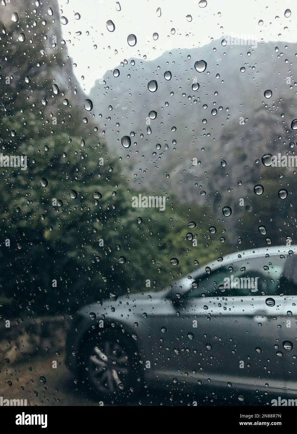 Raindrops on the clean car glass image with silver color car on the ...