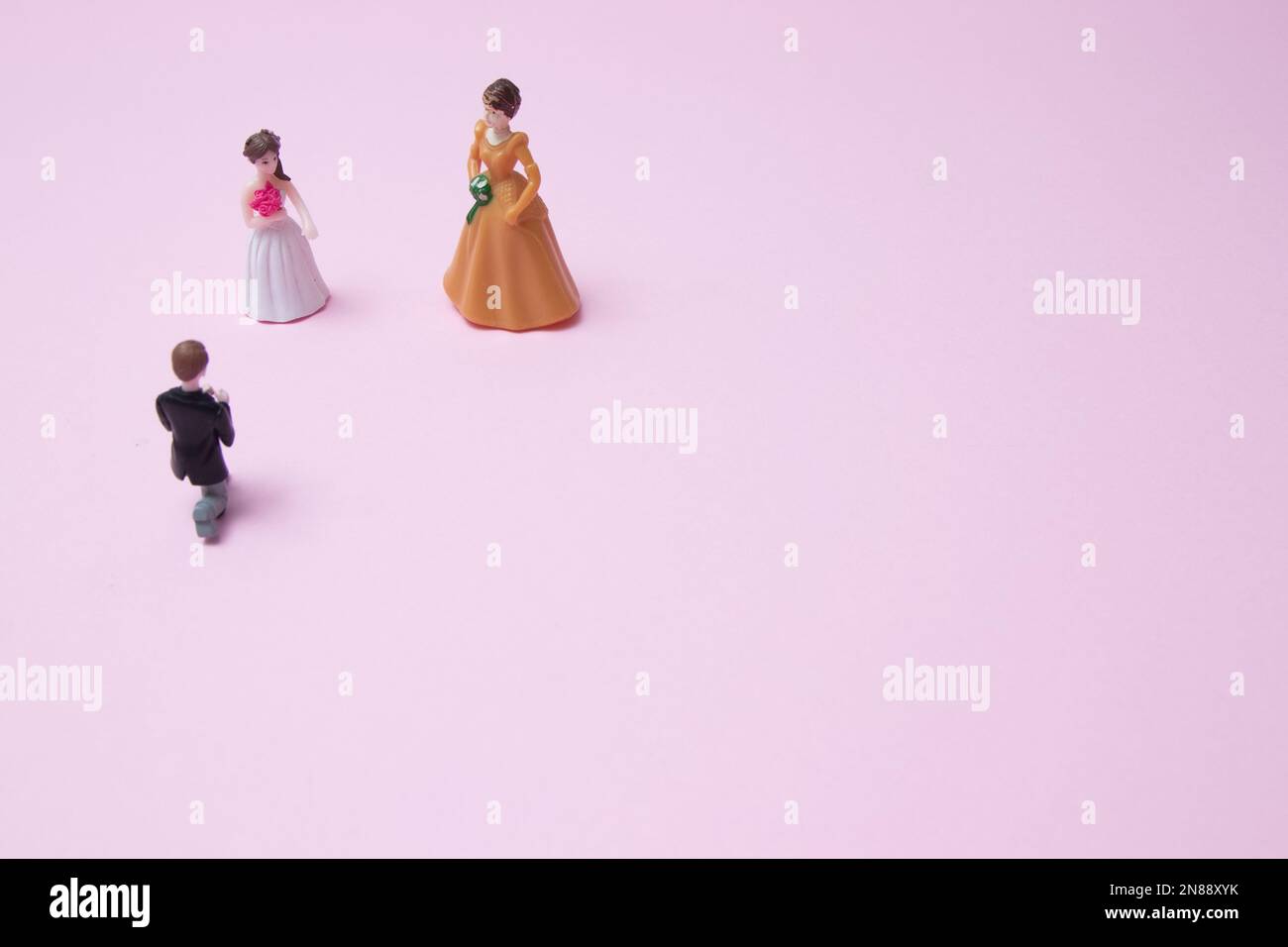 A minimal marriage proposal scene with figurines, on a pink background ...