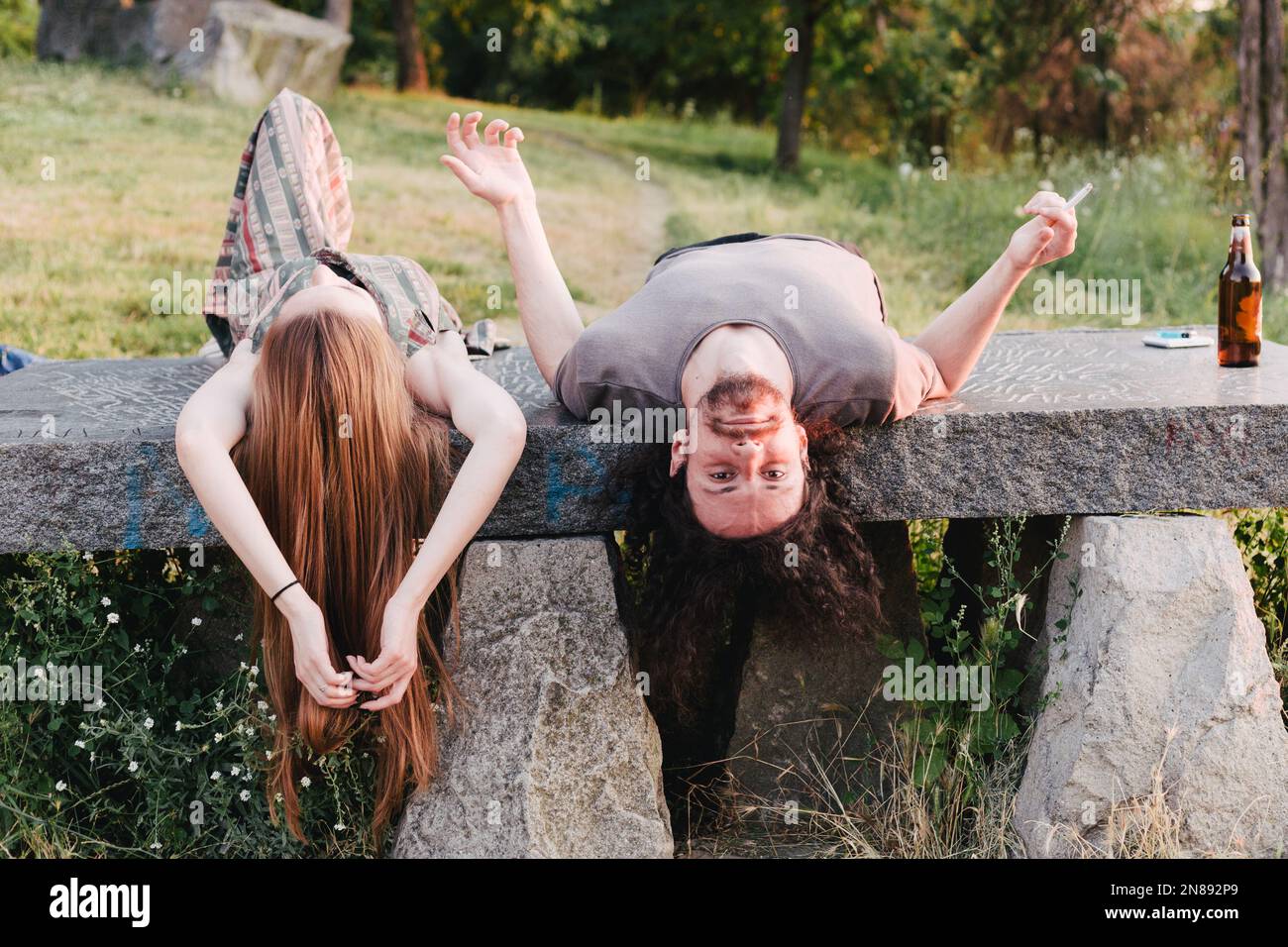 Couple lying in the park, enjoying the time together. Boyfriend smoking ...