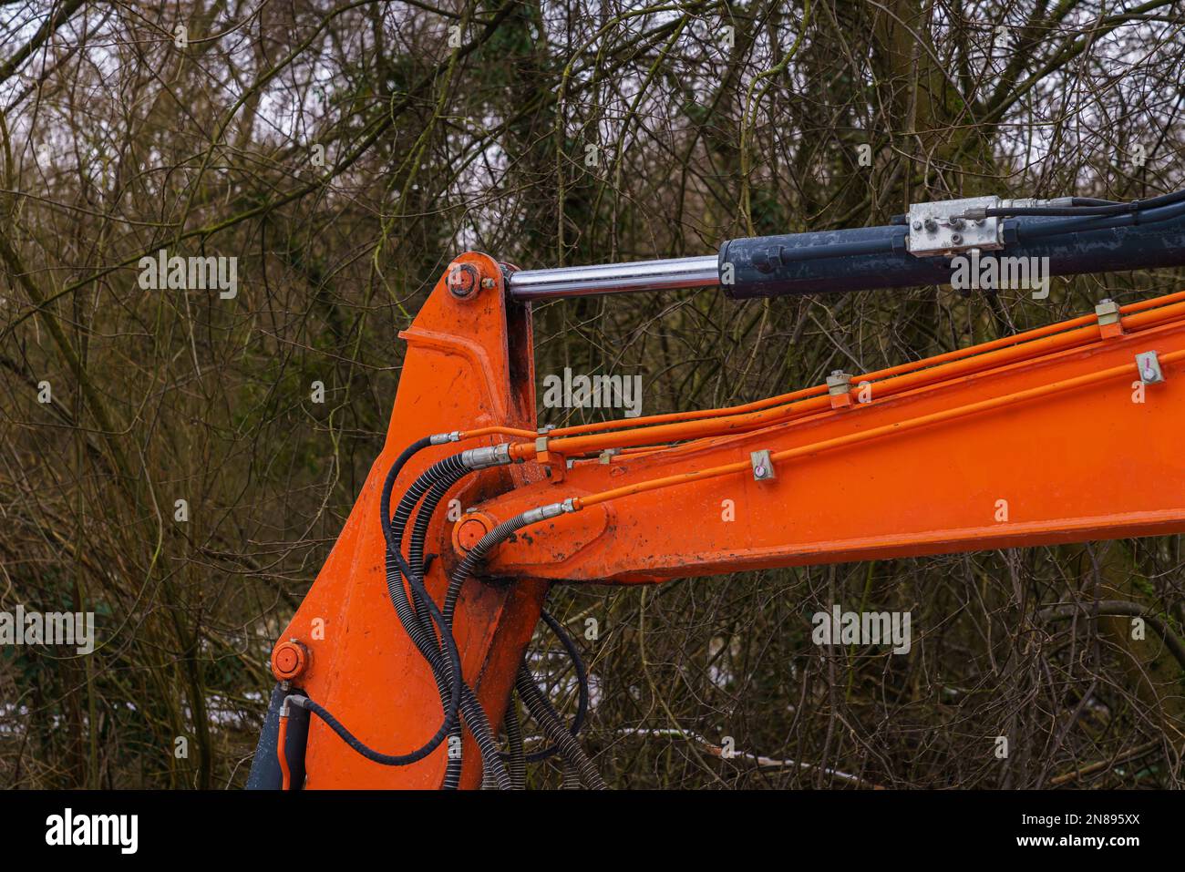 The hydraulic part of the excavator boom against the background of tree ...