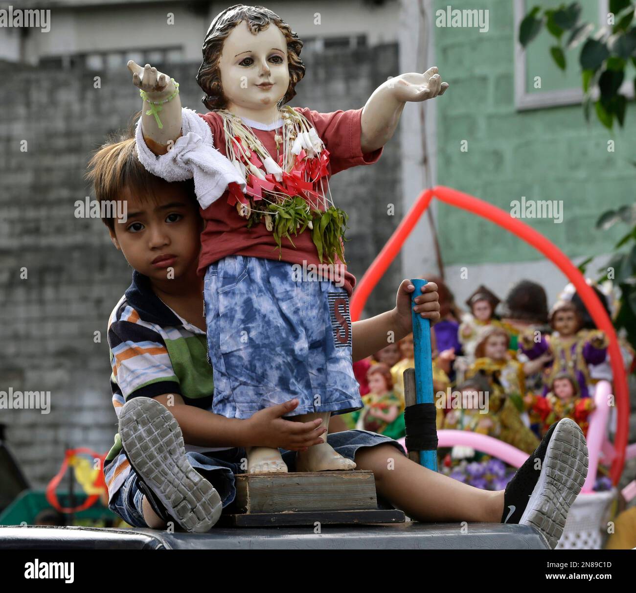 A boy holds a statue of the Infant Jesus while joining a procession to ...