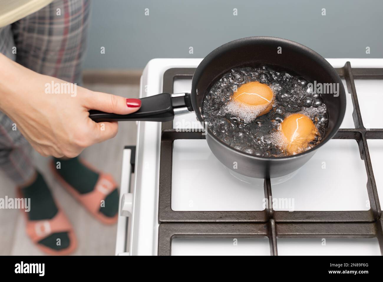 woman in the kitchen boils a chicken egg in water. chicken egg cooking ...