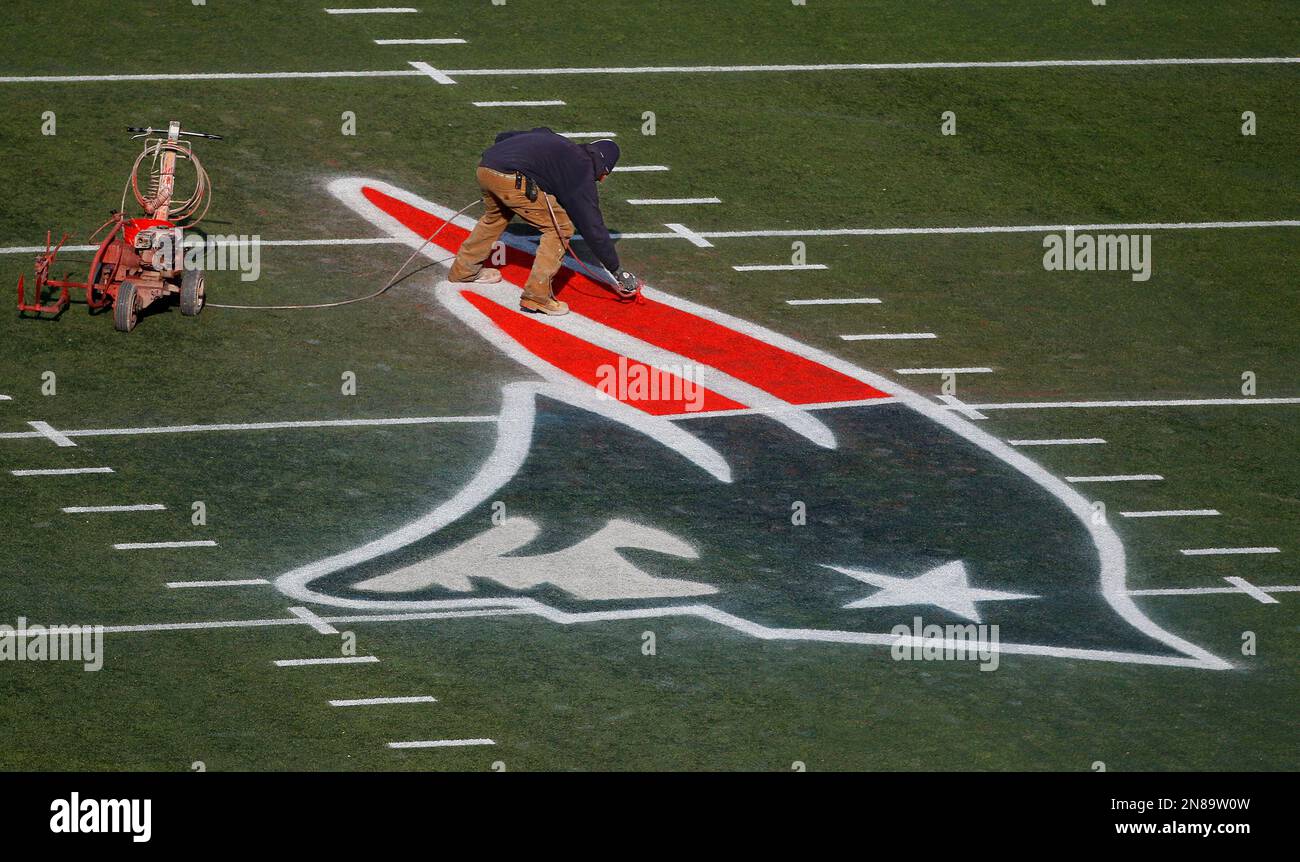 A member of the field crew touches-up the New England Patriots logo on ...