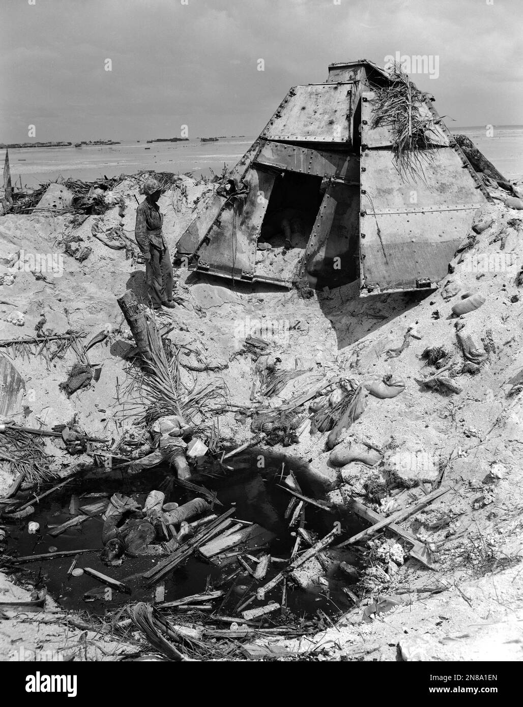Two dead Japanese lie in this shell crater and another sprawls inside ...