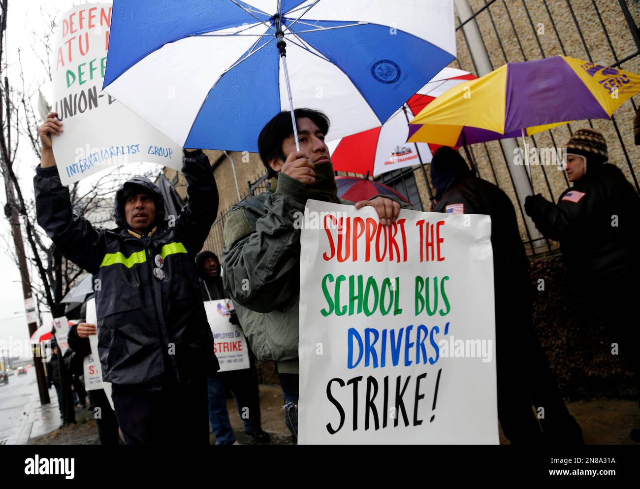 Bus drivers and supporters walk a picket line in front of a bus depot ...