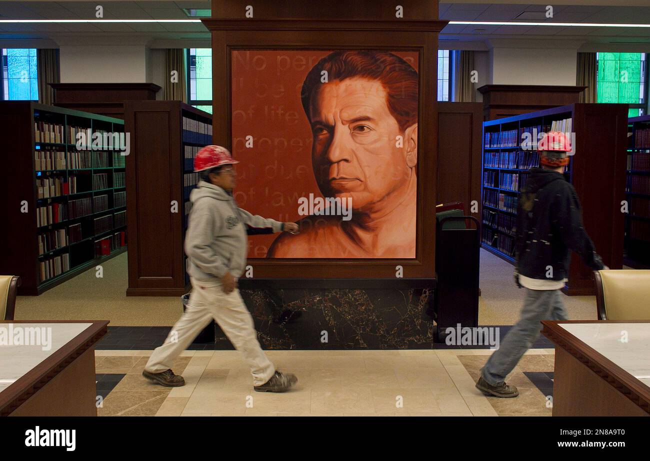 Workers walk past one of the portrait paintings, titled "The Face of ...