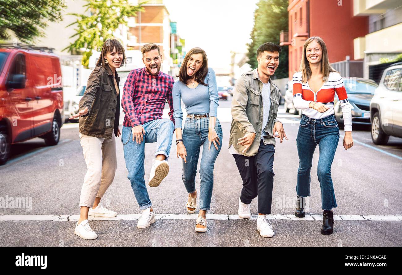 Happy diverse students walking at city center acting funny crazy moves ...