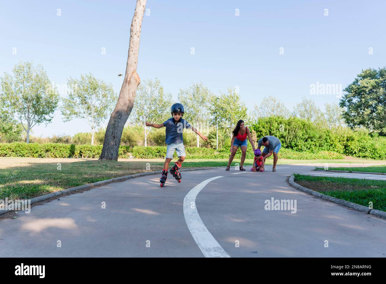 Kids holding her parents hands while roller skating outdoors in the ...