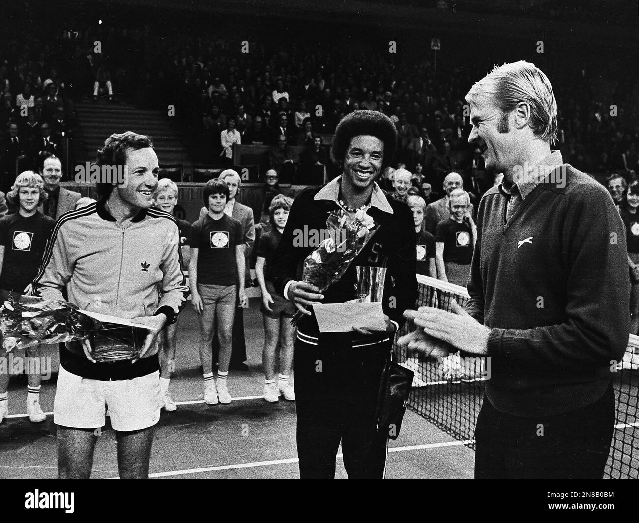 Two happy tennis players, Tom Okker, left and Arthur Ashe, center, with ...