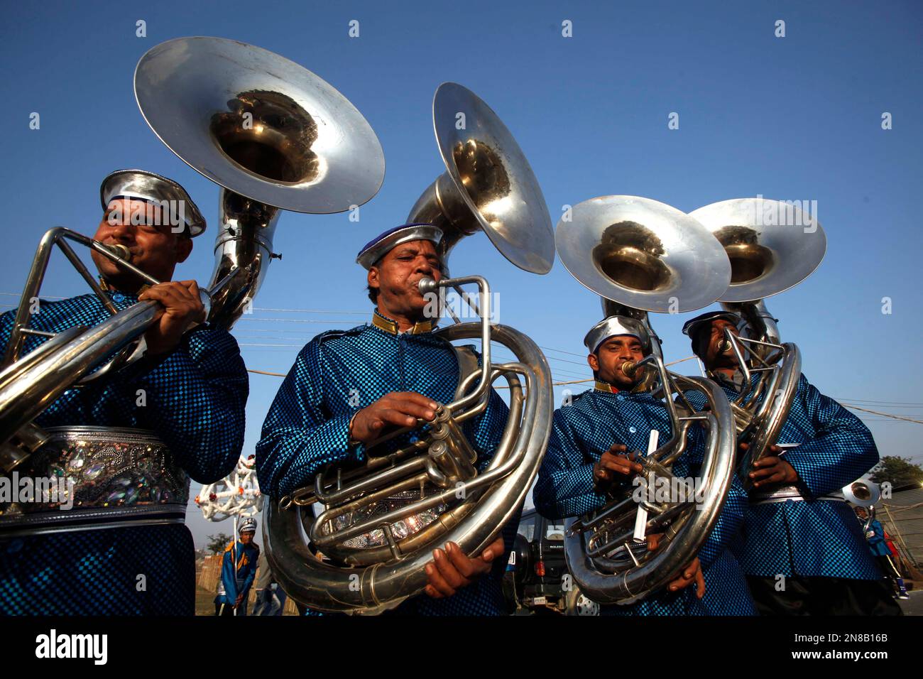 An Indian brass band members blow their wind instruments during a ...