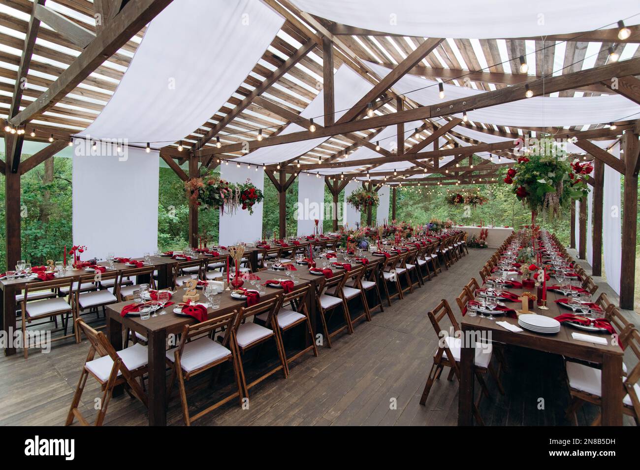 A large, long, decorated, wooden table and chairs, with dishes, flowers ...