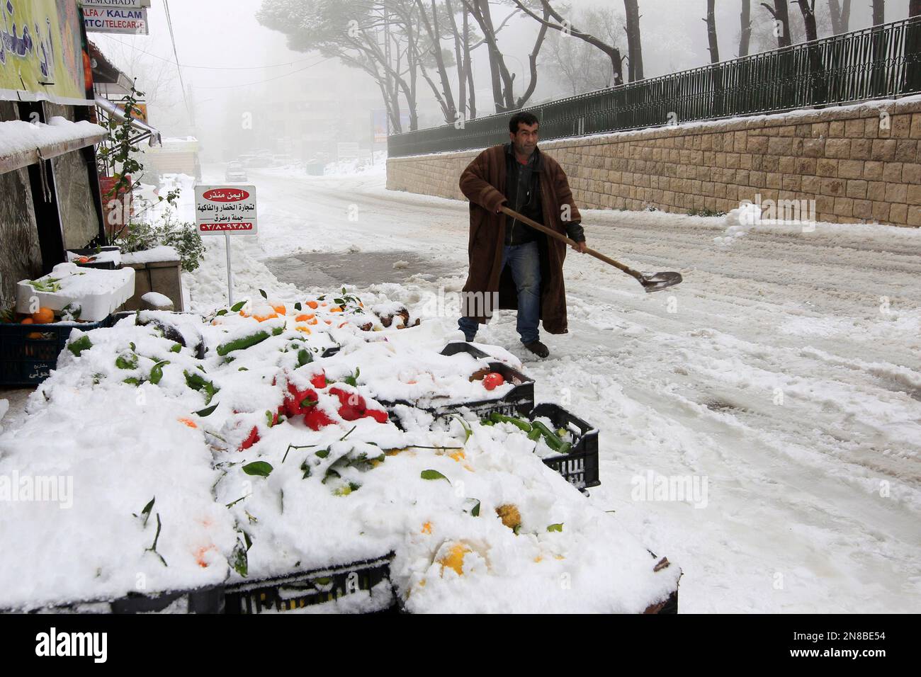 A Lebanese man clears snow in front of his shop at the mountain town of ...