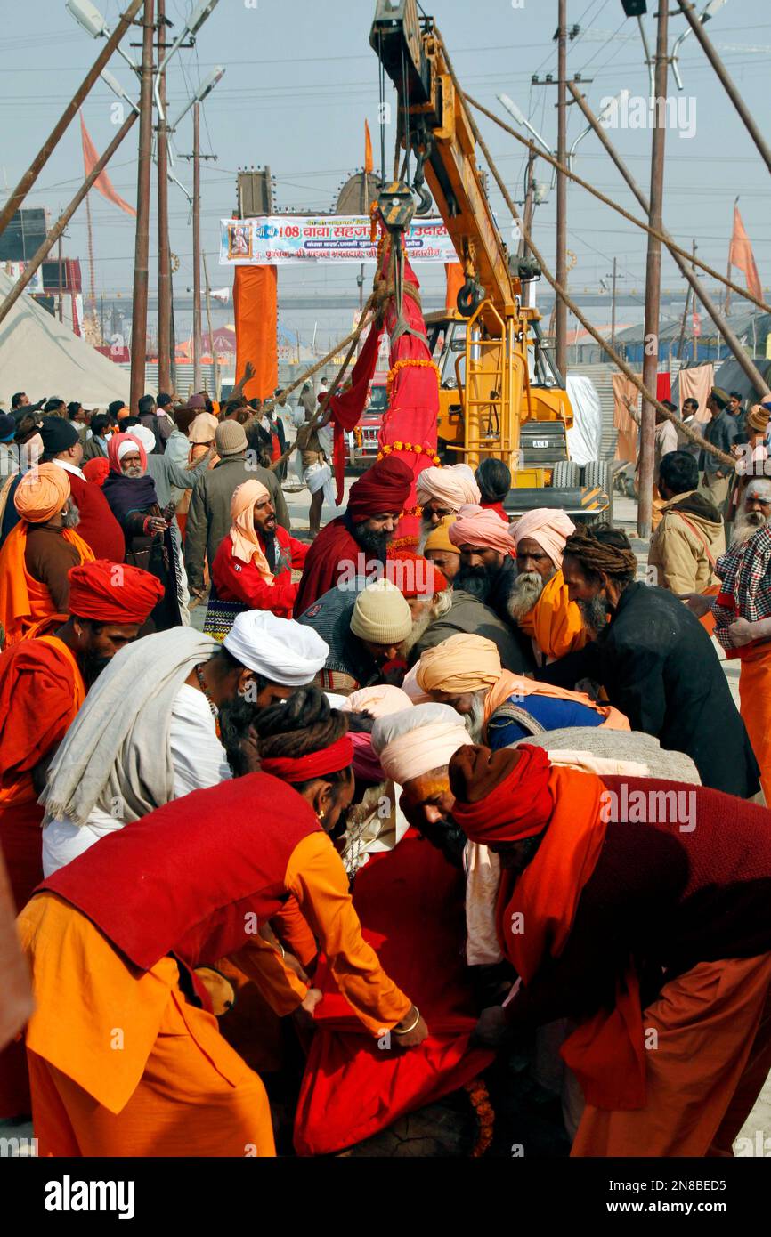 Sadhus, or Hindu holy men, pull bamboo covered with a cloth to raise a ...