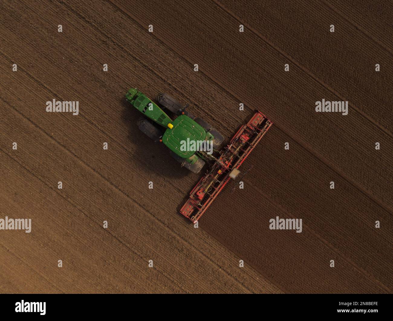 A John Deere tractor, seen from above, cultivates a field in ...