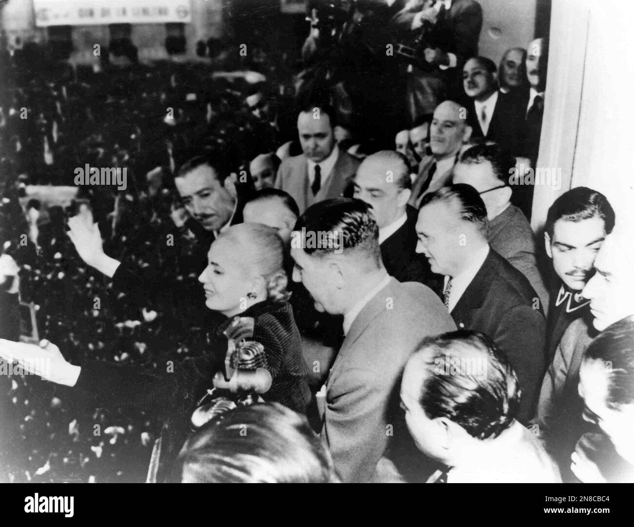 Argentine President Juan Peron stands behind his Eva as she waves to ...