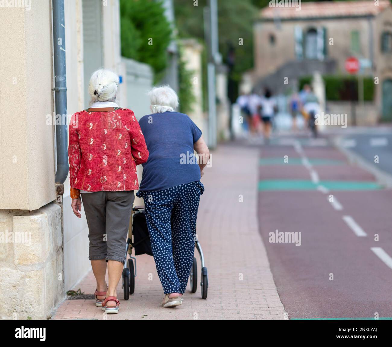 woman walking on the sidewalk using a walker Stock Photo - Alamy
