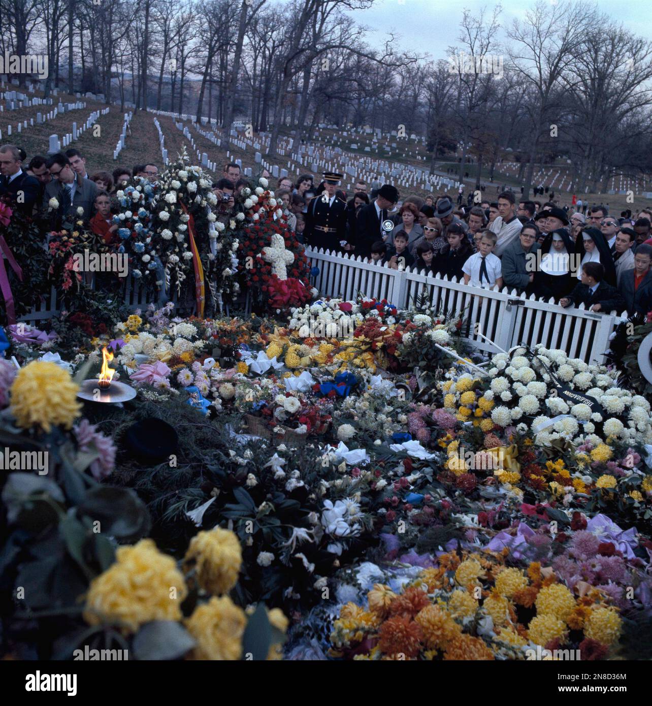 Mourners stand at the flower-bedecked grave of President John F ...