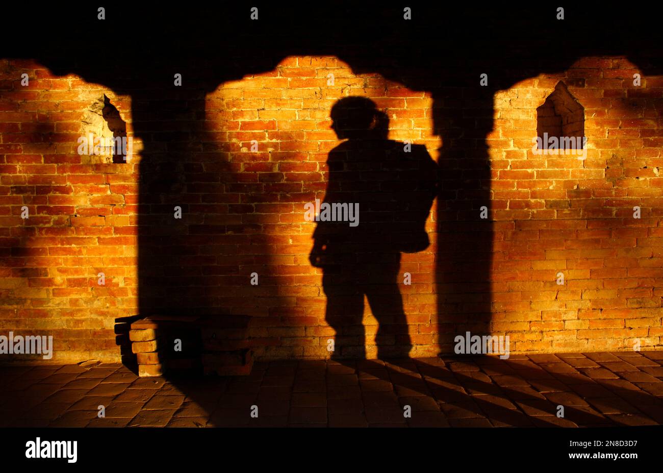 The shadow of a tourist falls on the wall of a temple near the ...