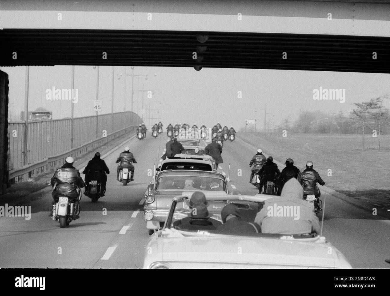 Motorcycle policemen ride ahead and on the flanks of the motorcade ...