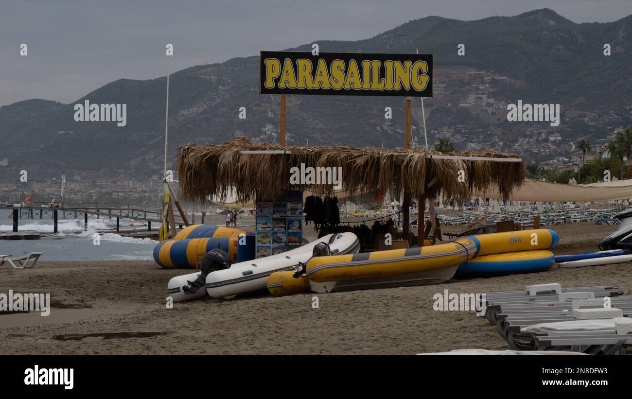 Colorful motor boats a Beach with Parasailing sign with green mountains ...